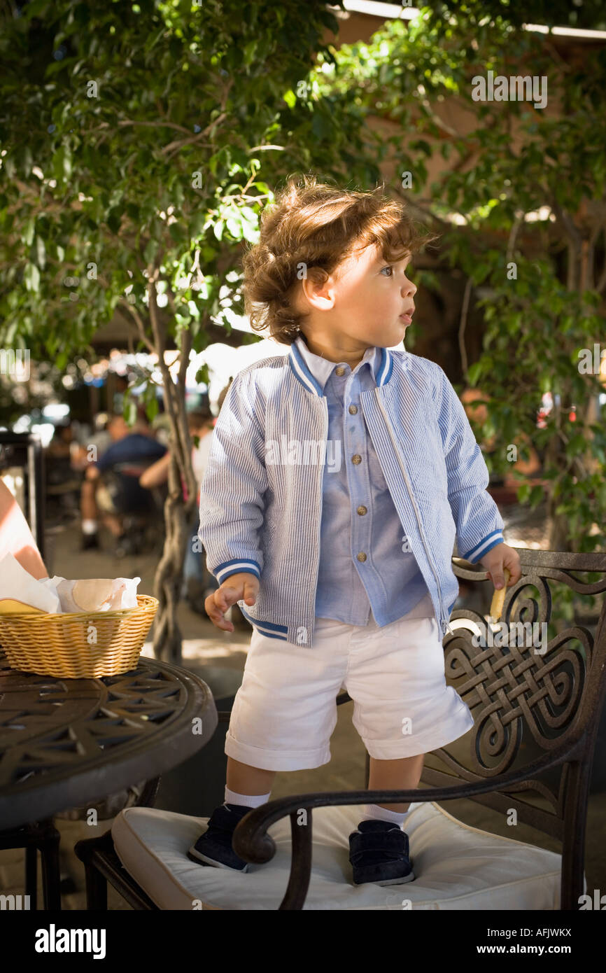 Baby boy standing on a chai Stock Photo - Alamy