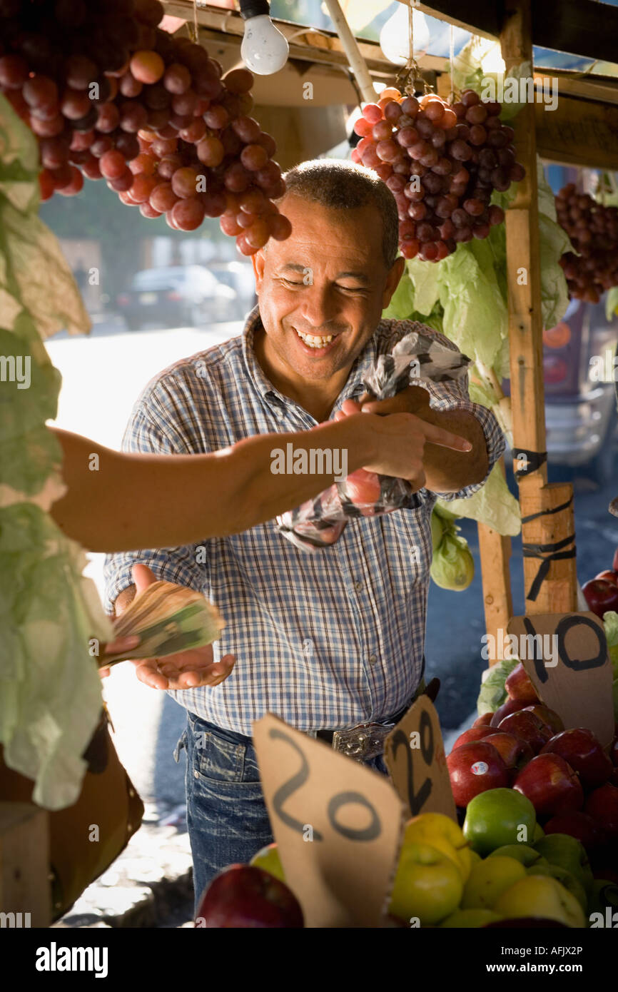 Fruit seller giving a plastic bag of fruits to customer Stock Photo - Alamy