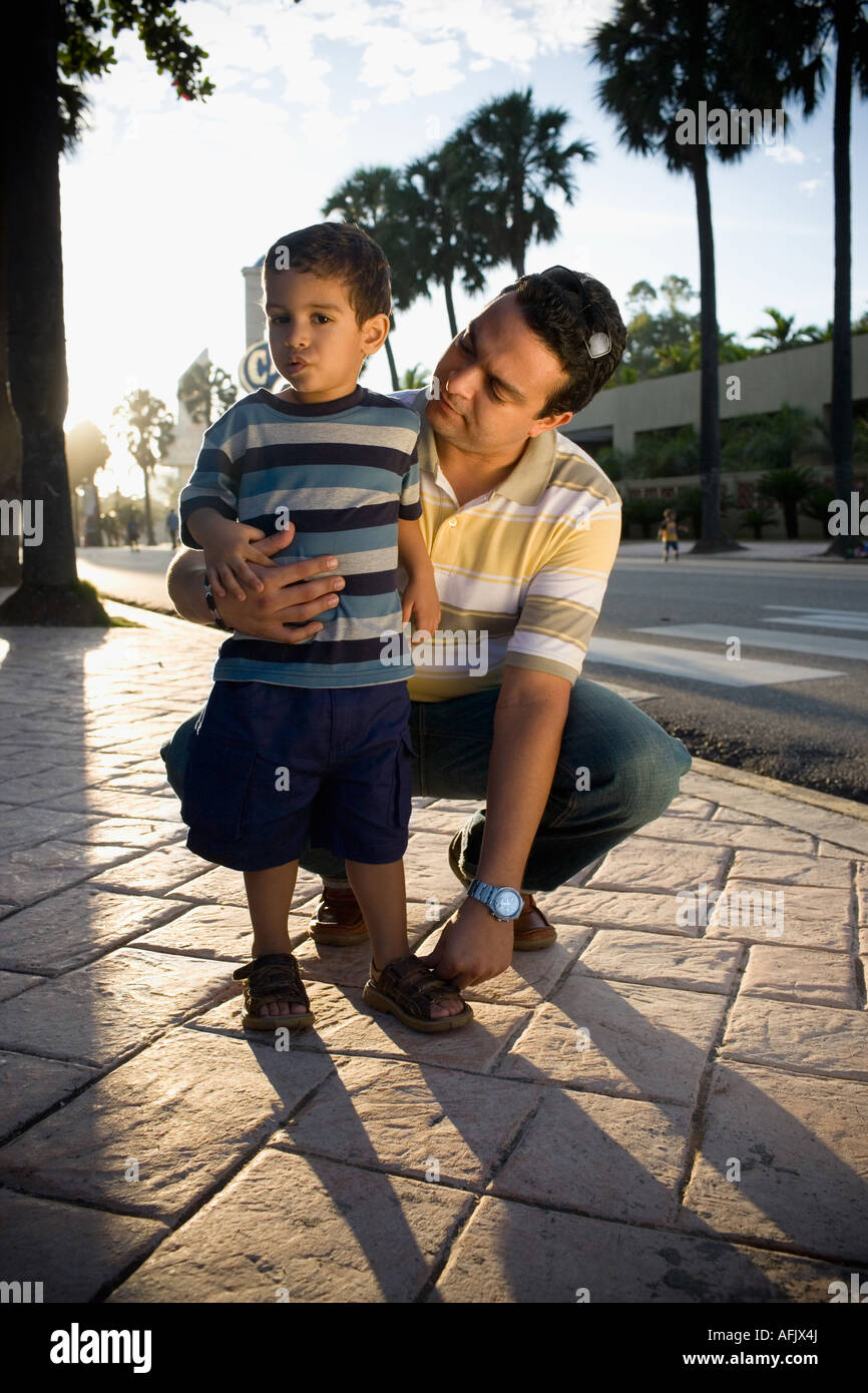 Mid adult man adjusting his son's sandals Stock Photo - Alamy