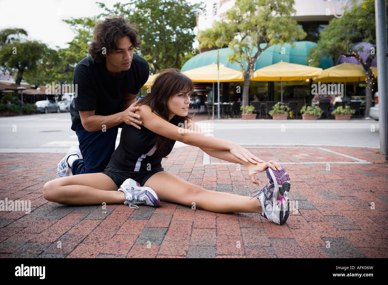 Young woman stretching with physical trainer Stock Photo - Alamy