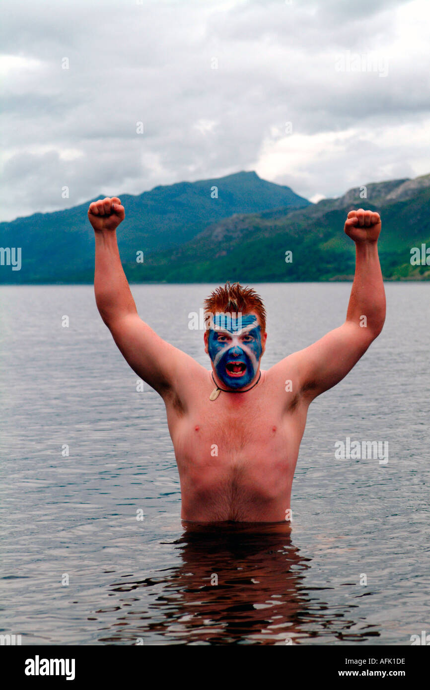 A Scotsman wearing the Scottish flag colours painted onto his face ...