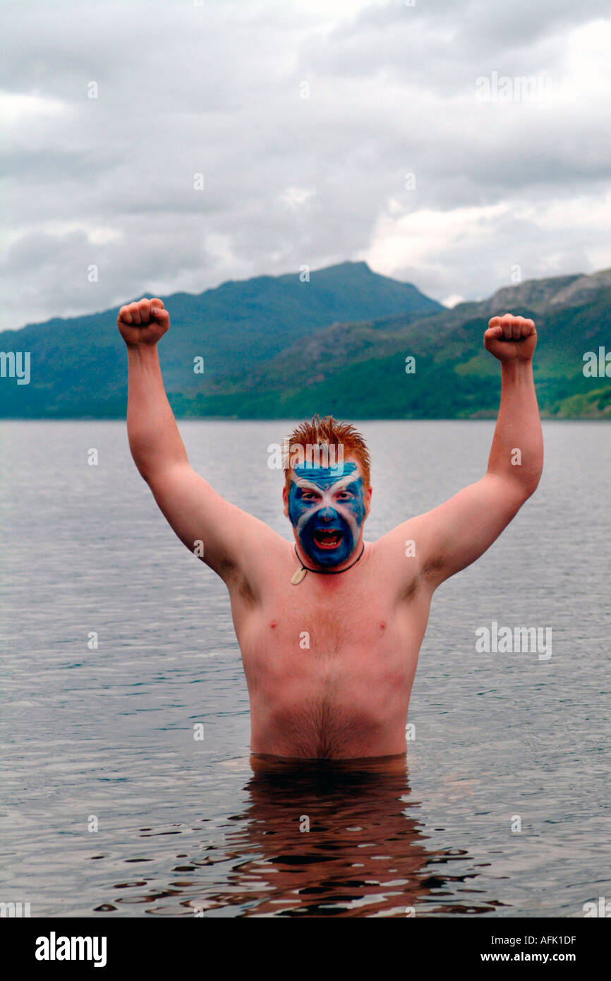 A Scotsman wearing the Scottish flag colours painted onto his face ...
