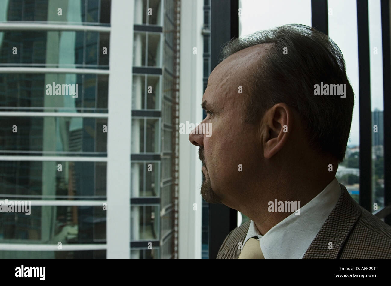 Businessman looking out office window Stock Photo - Alamy