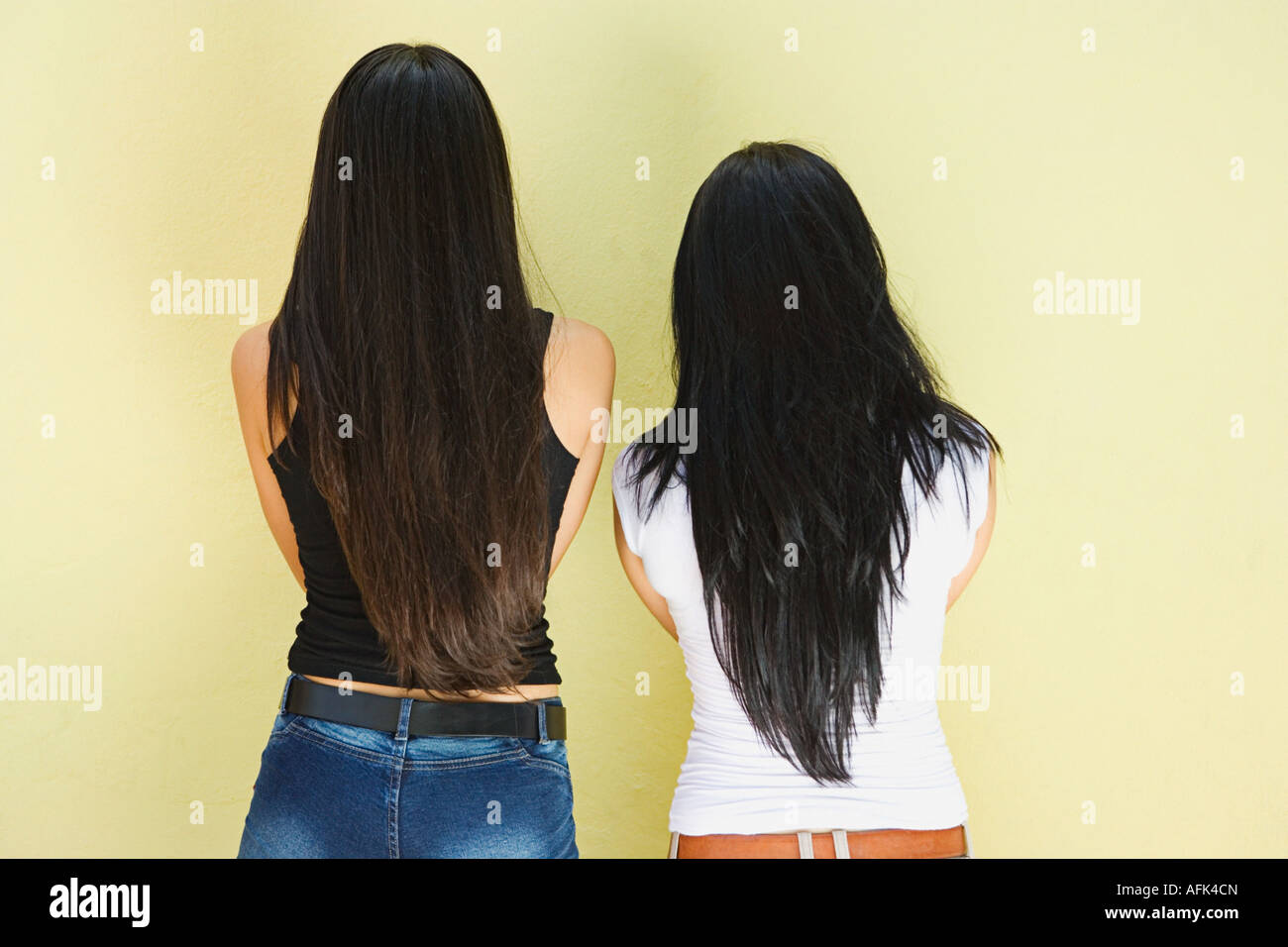 Two young women standing against wall Stock Photo - Alamy