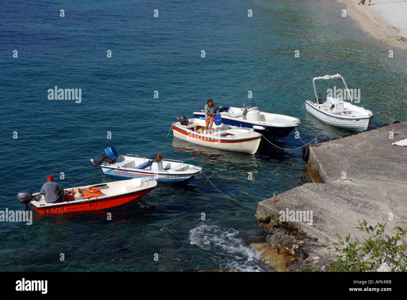 Five small boats with outboard motors moored to jetty and being ...