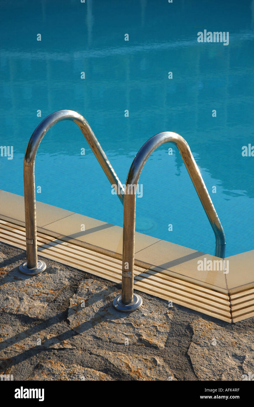 Swimming pool hand rail in early morning sun. Water in pool beyond dead ...