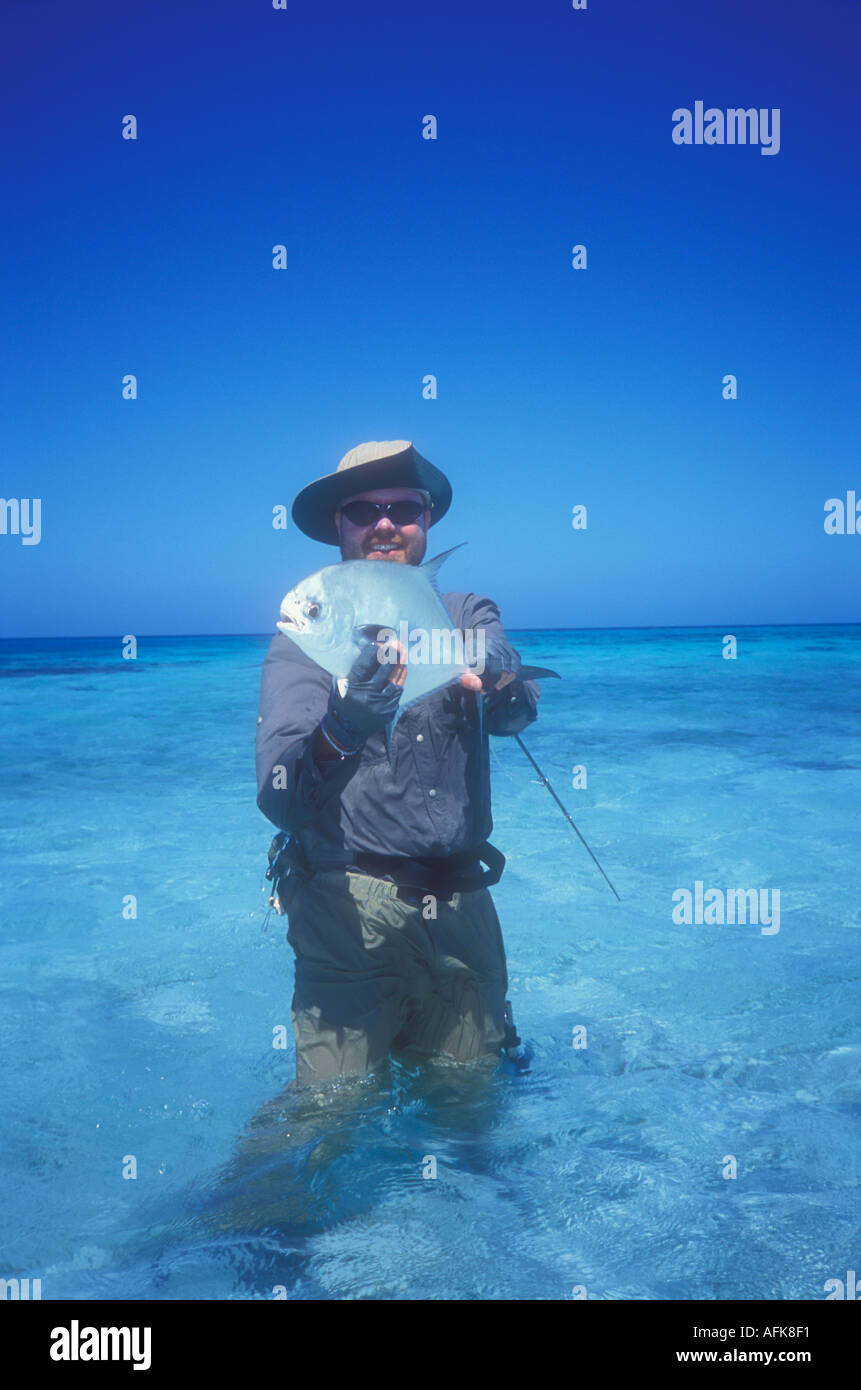 Man holding permit fish caught while fly fishing in Belize Caribbean ...