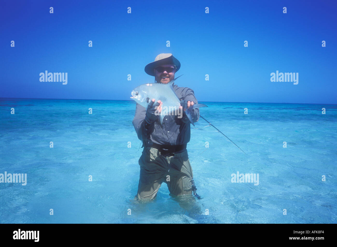 Man holding permit fish caught while fly fishing in Belize Caribbean ...