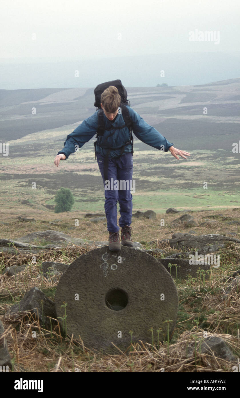 A climber balances on an abandoned Millstone below Stanage Edge in the ...