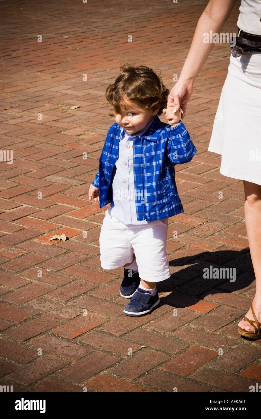 Baby boy holding his mother's finger and walking Stock Photo - Alamy