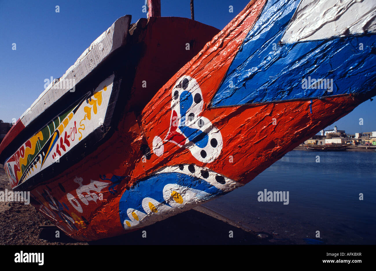A brightly painted fisherman's boat rests on the banks of the Senegal ...