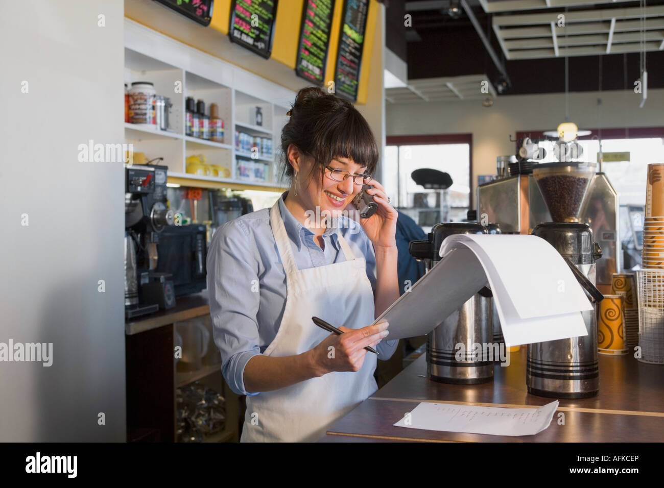 Female store clerk talking on a cordless phone in a coffee shop Stock ...