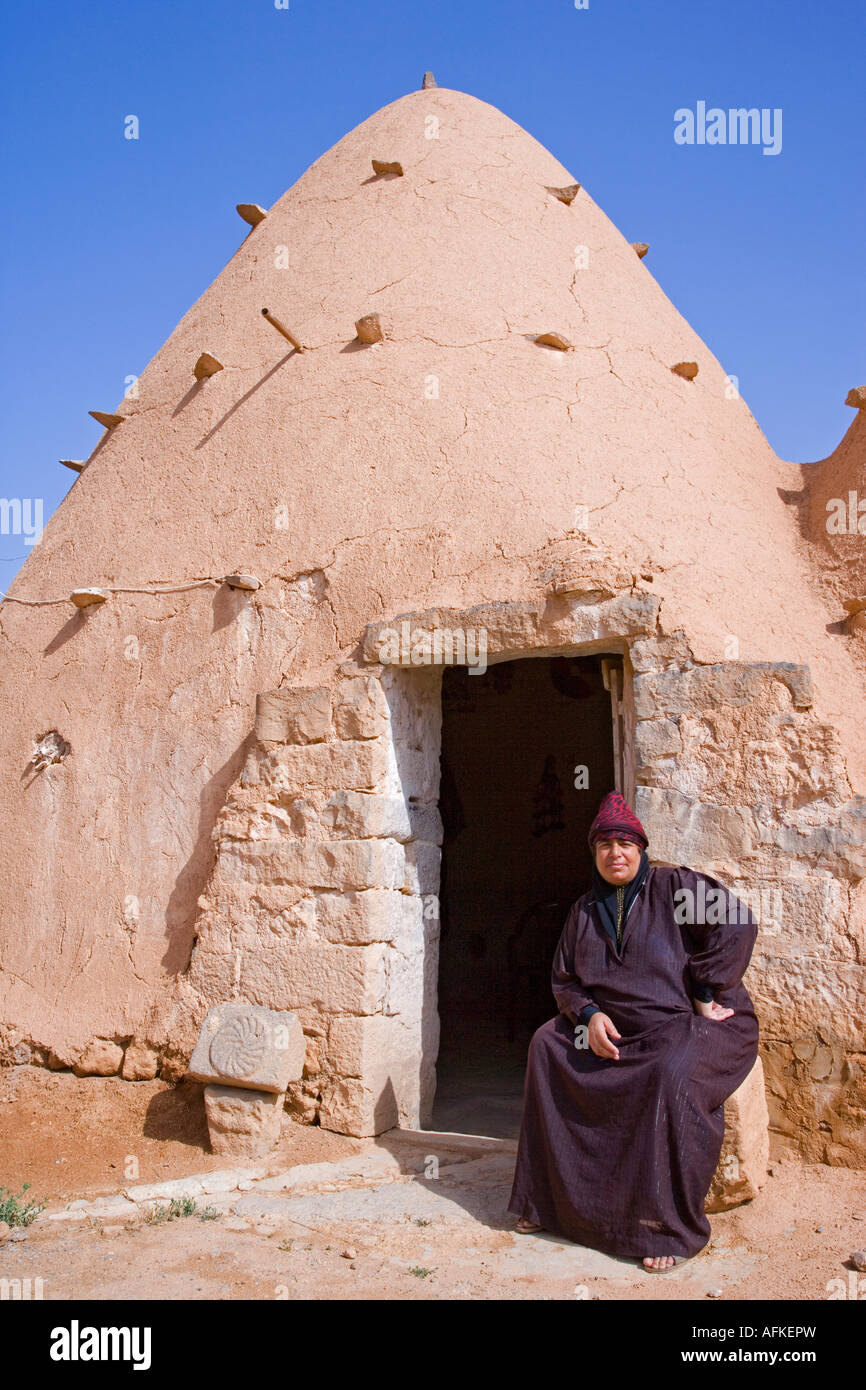 A woman sits in front of her traditional beehive house in the village ...