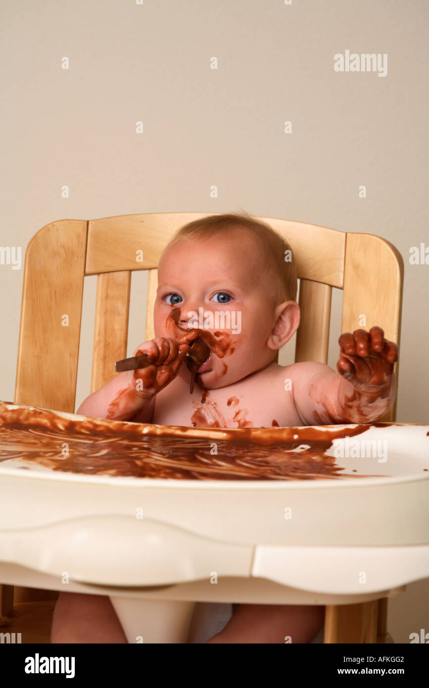 Baby in highchair making mess with chocolate pudding Stock Photo - Alamy