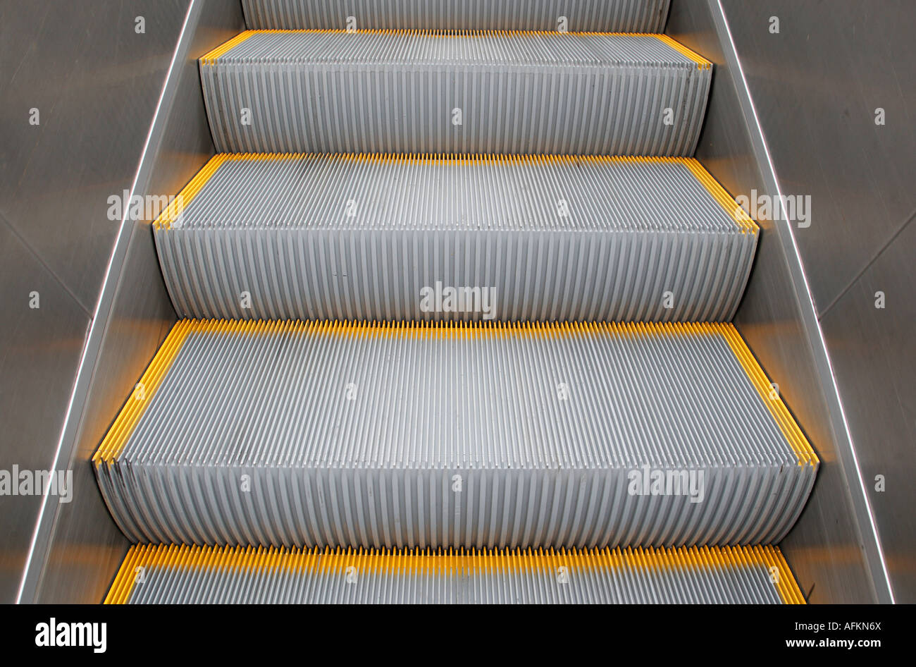 steps on a escalator with a yellow demarkation line to indicate the ...