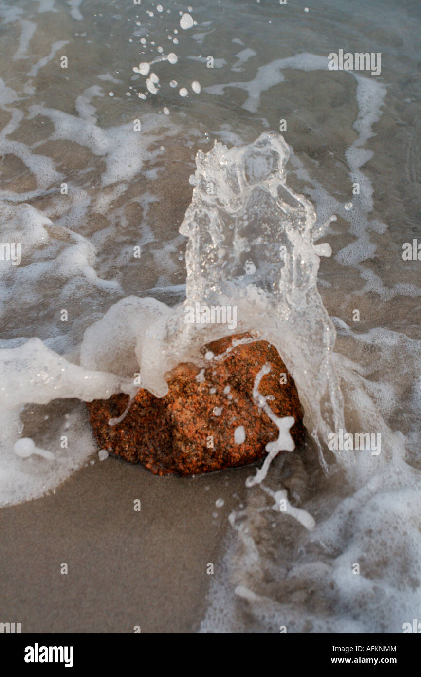 Water splashing against a rock on a beach Stock Photo - Alamy