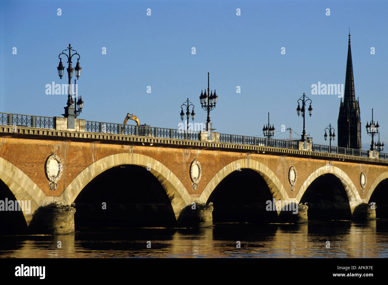The Pont de Pierre over Garonne river, with the spire of the Basilica ...