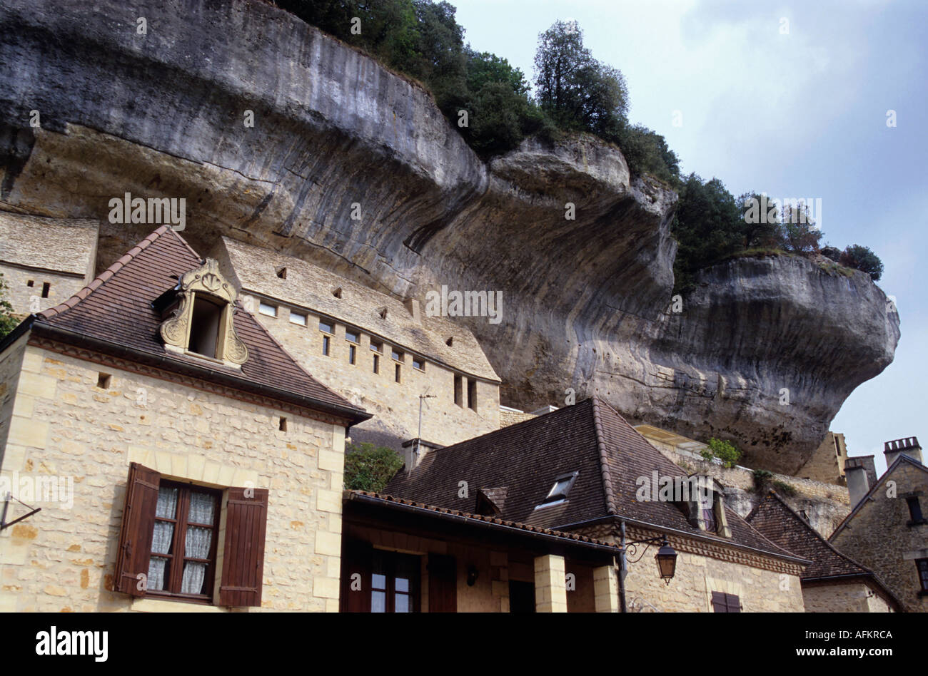 Medieval buildings beneath an overhanging rock face, Les Eyzies-de ...