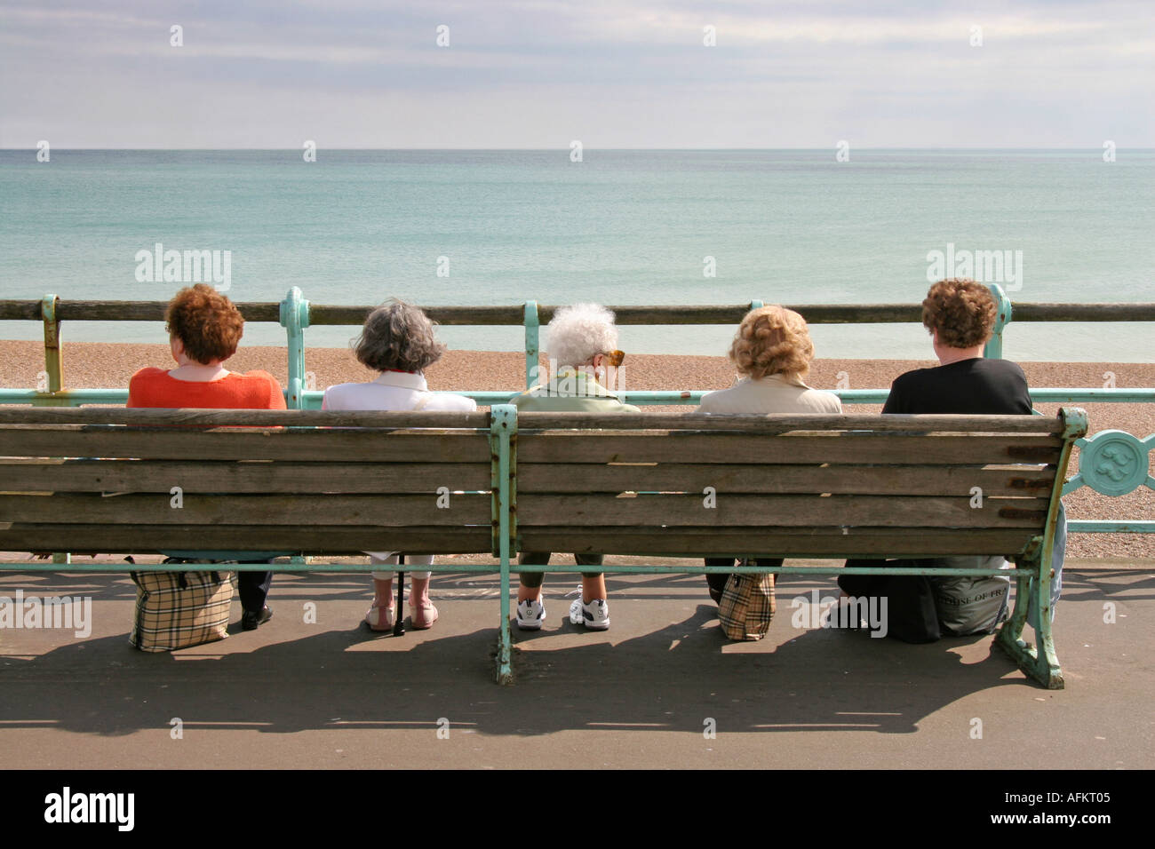 a group of five eldery ladies sitting on a wrought iron bench on the ...