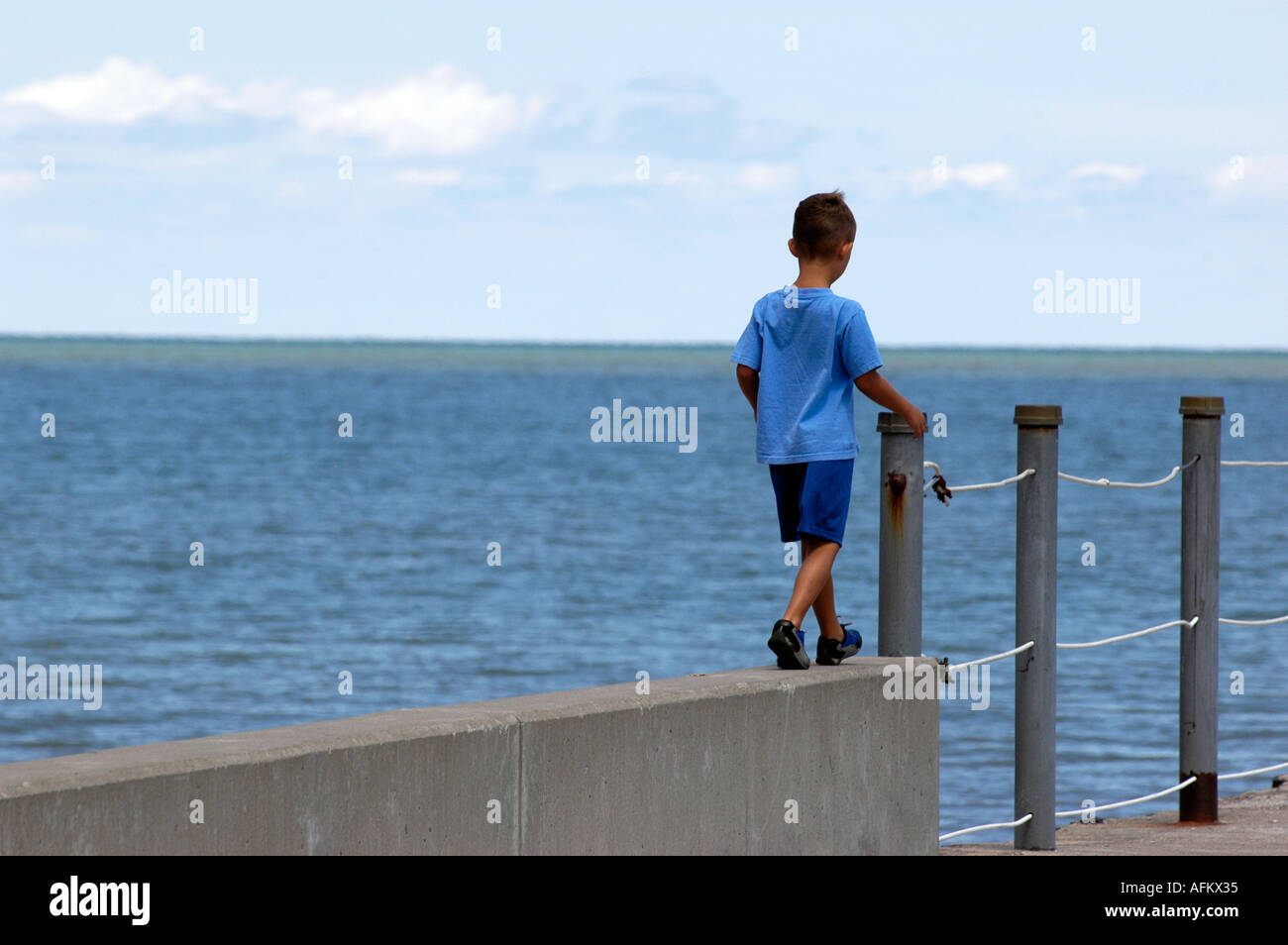 Lone boy on pier Stock Photo - Alamy