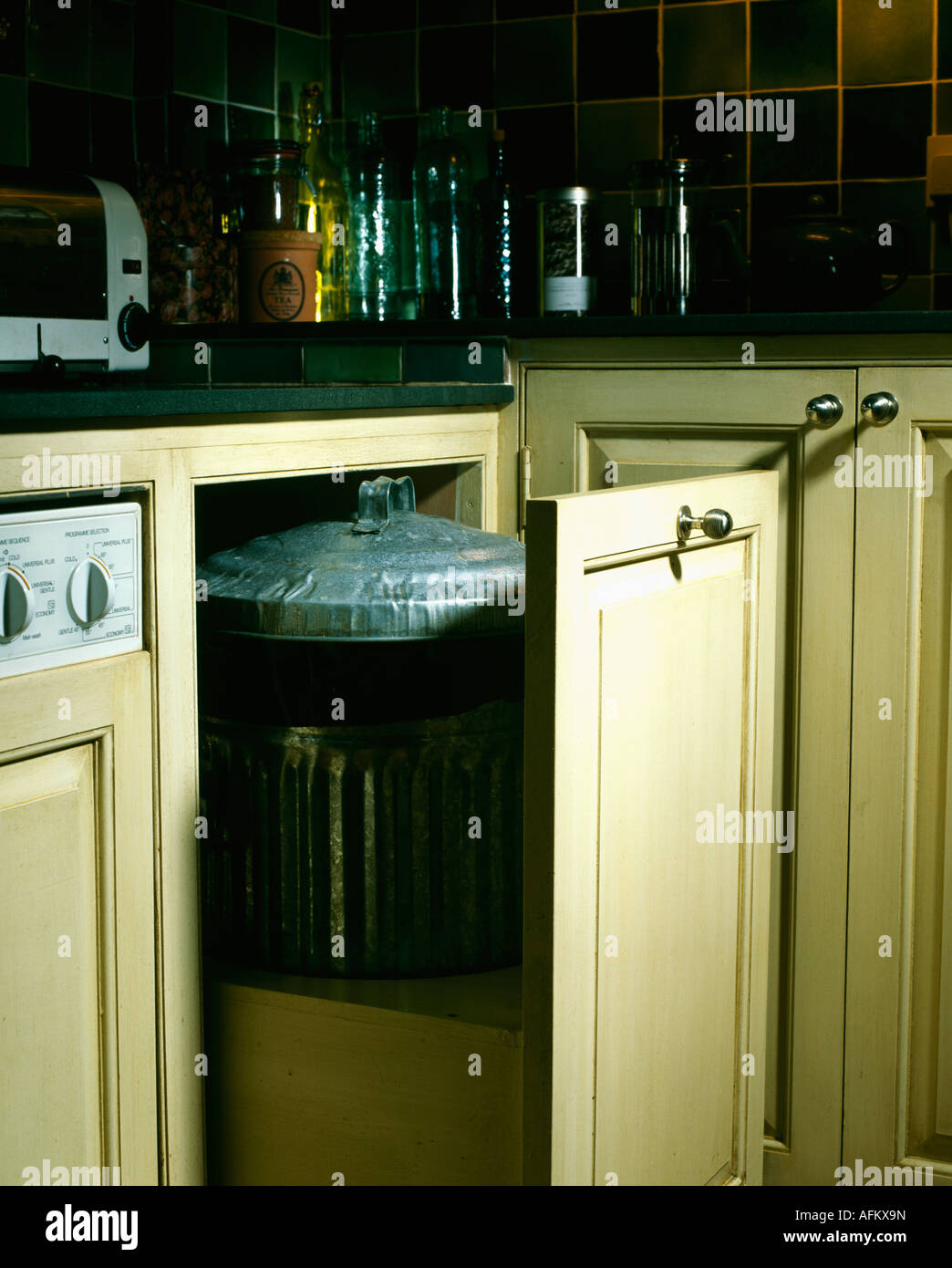 Kitchen cupboard door open to show galvanised wastebin Stock Photo - Alamy
