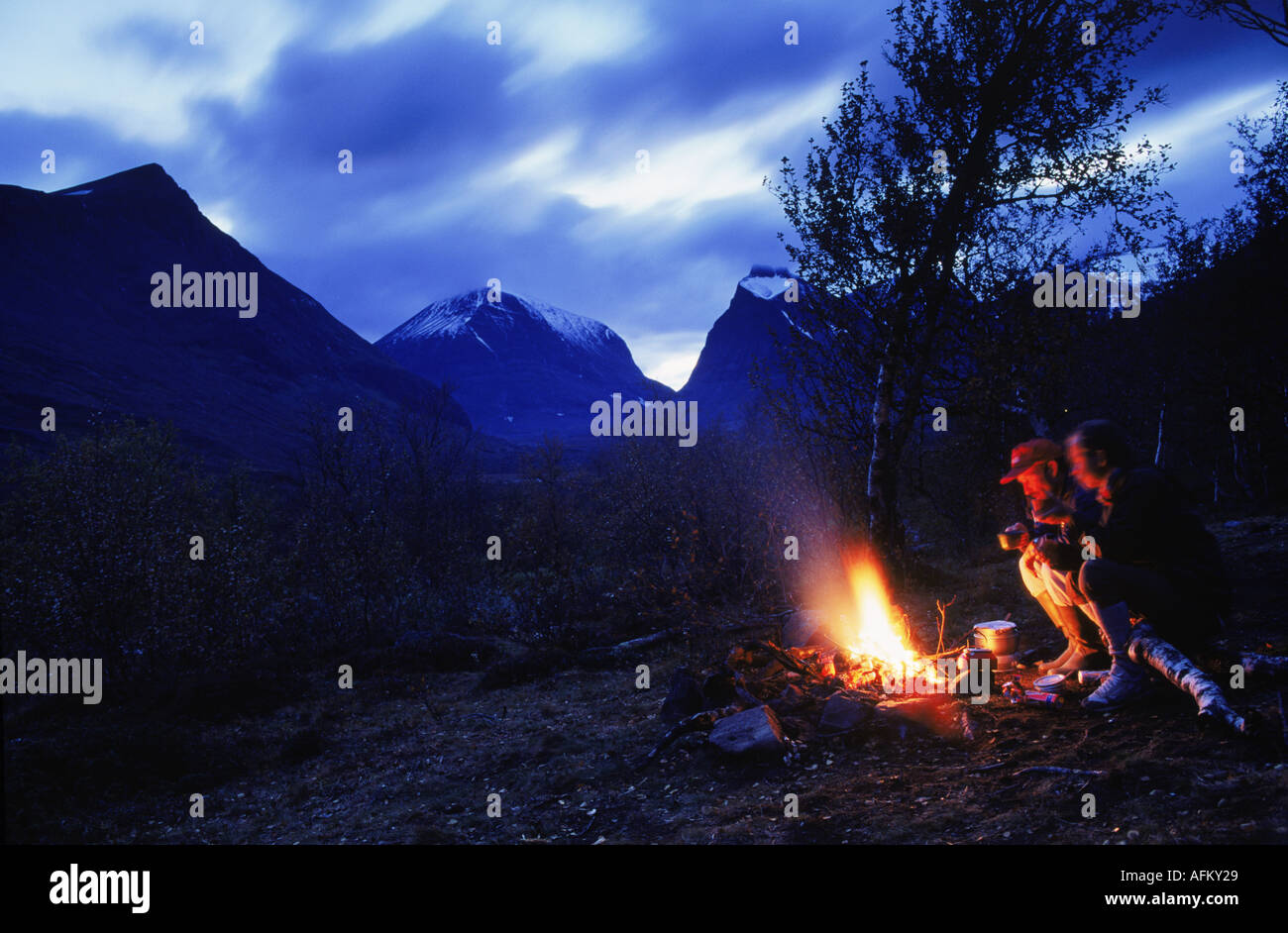 Two hikers sitting next to campfire in Swedish Arctic wilderness called ...