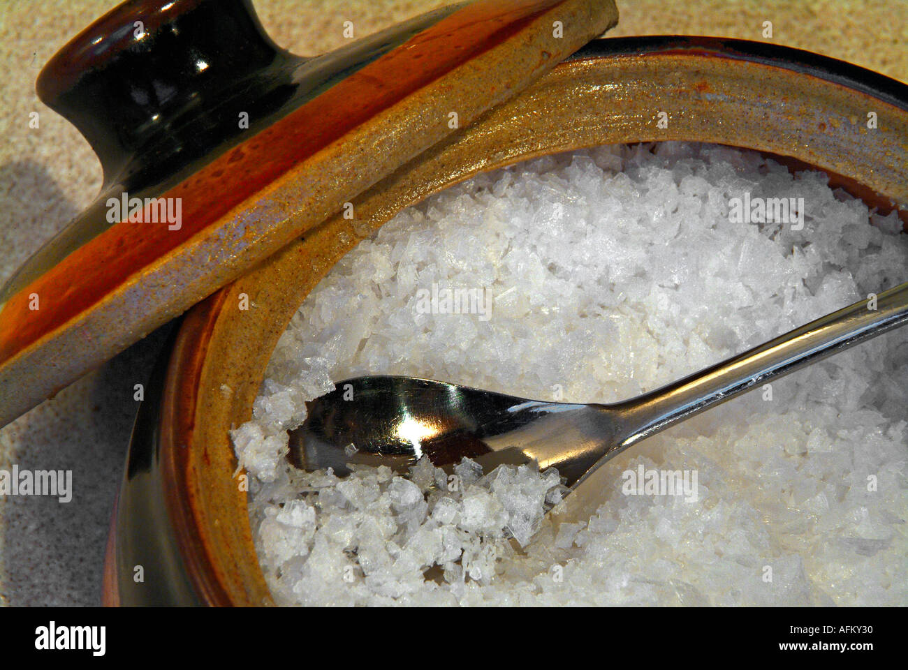 rock salt sea salt granules in a handmade pottery bowl with teaspoon ...