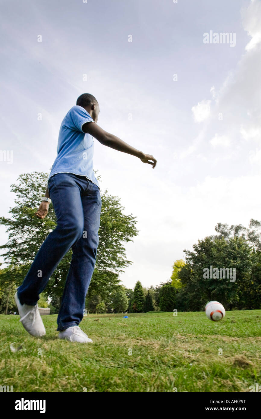 Young Black man playing football in the Park on a summers day Stock ...