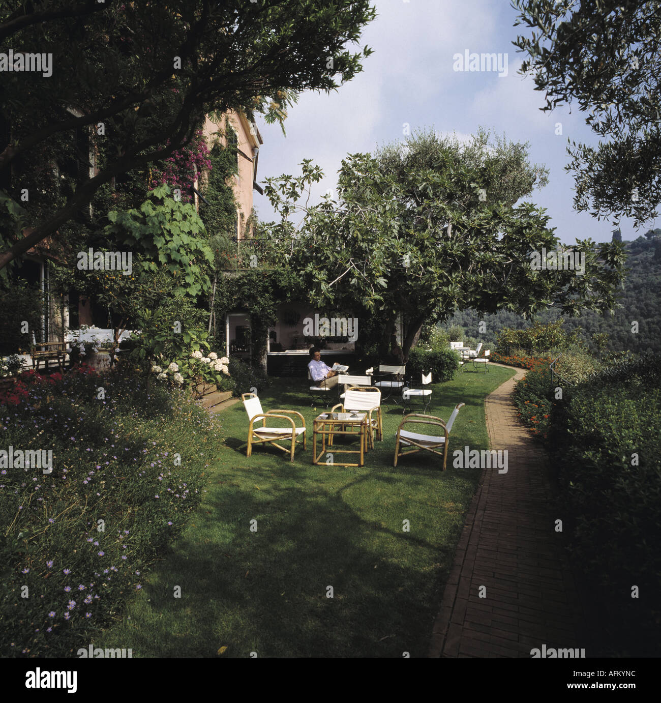 Gravel path beside lawn with chairs and table in garden of Italian ...
