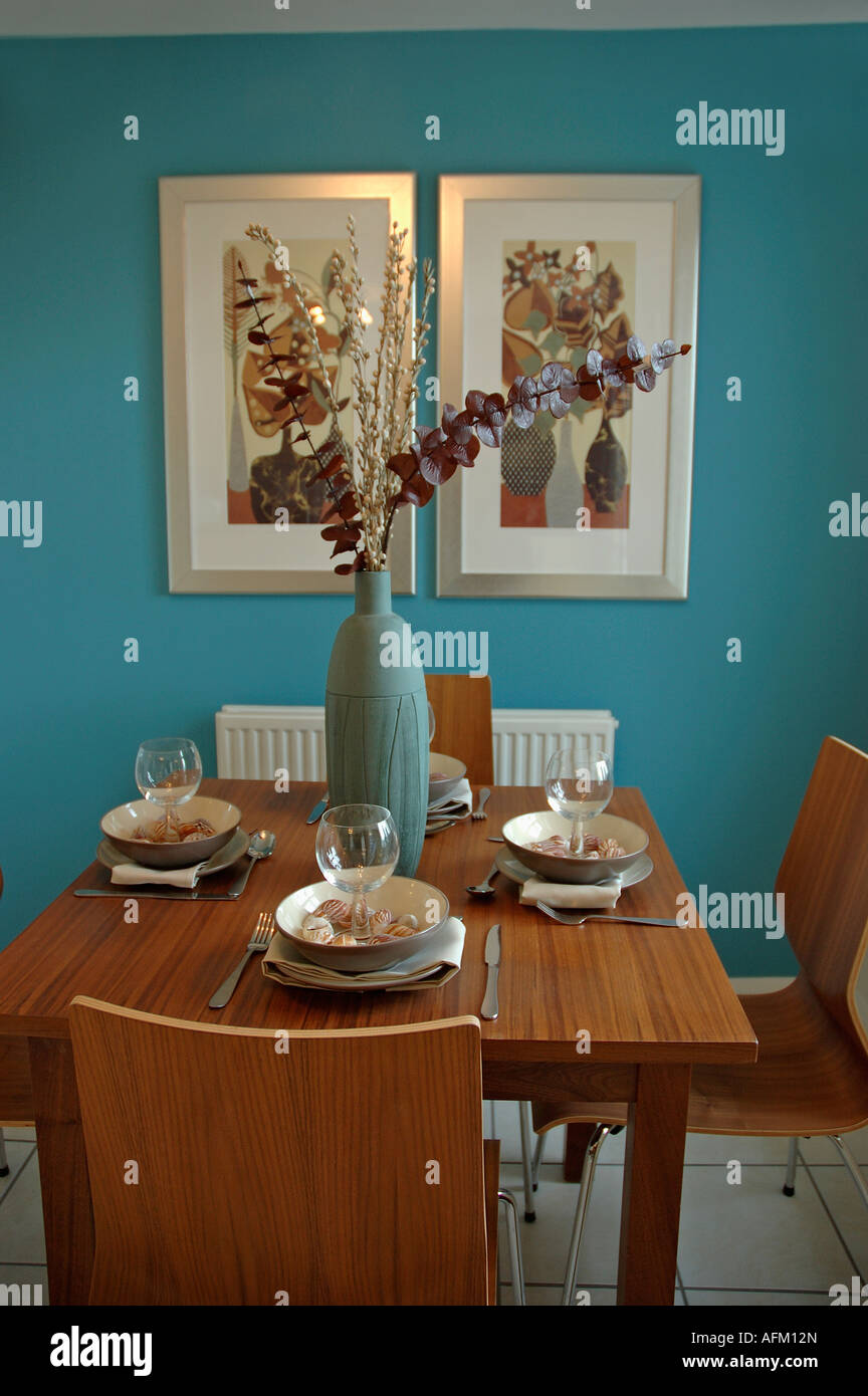 Simple floral arrangement on modern wood table set for dinner in ...