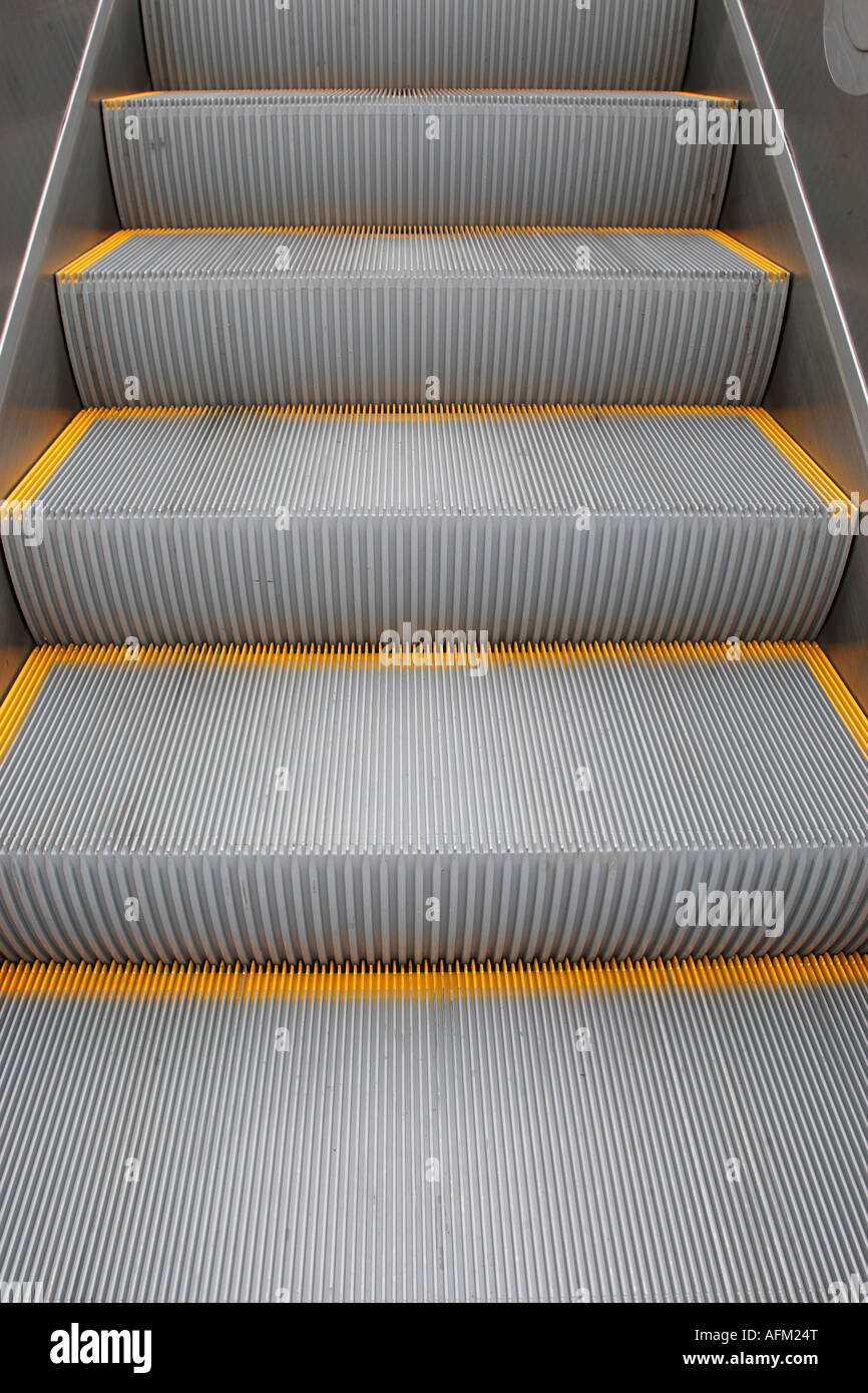 steps on a escalator with a yellow demarkation line to indicate the ...