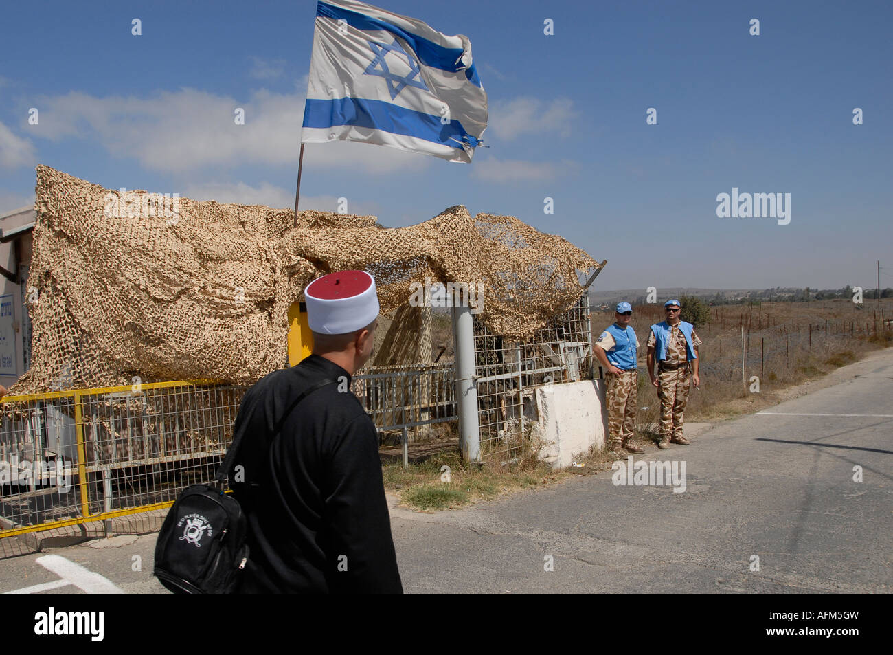 A Druze man walks past peacekeepers of the United Nations UNDOF force ...