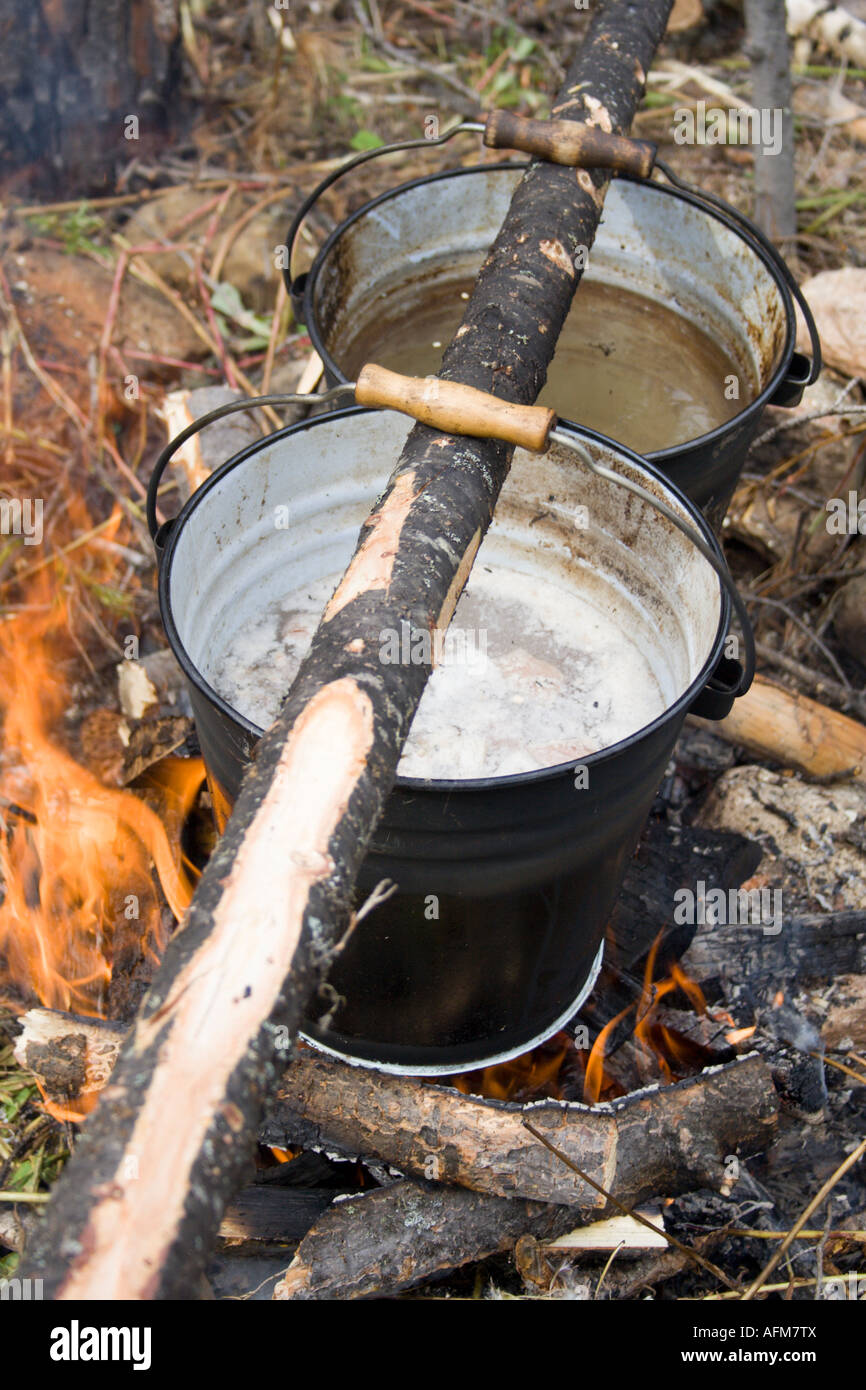Boiling water in pails above the fire in camping Stock Photo - Alamy