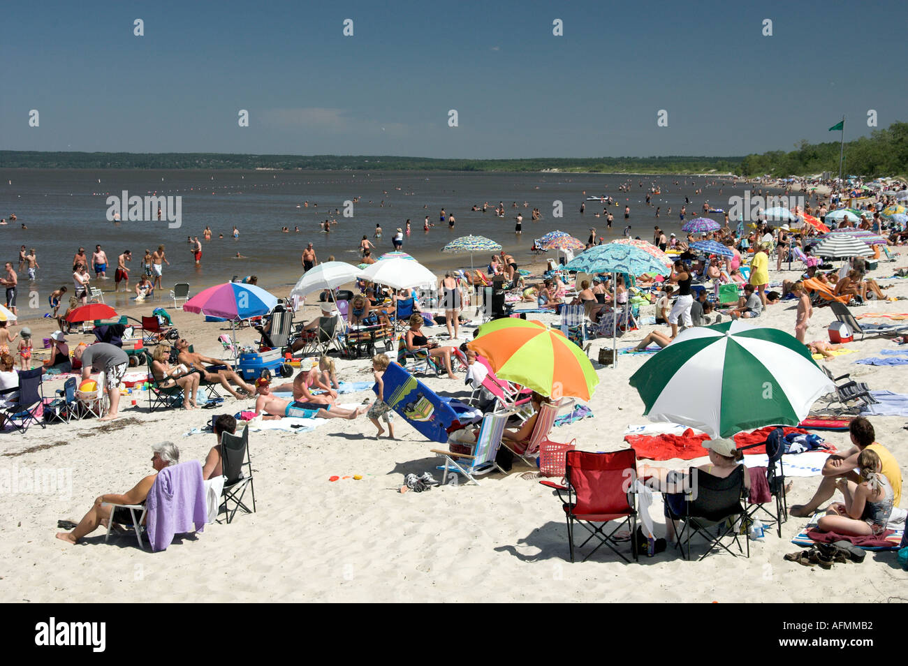 Beach scene with sunbathers and colorful umbrellas at Grand Beach ...