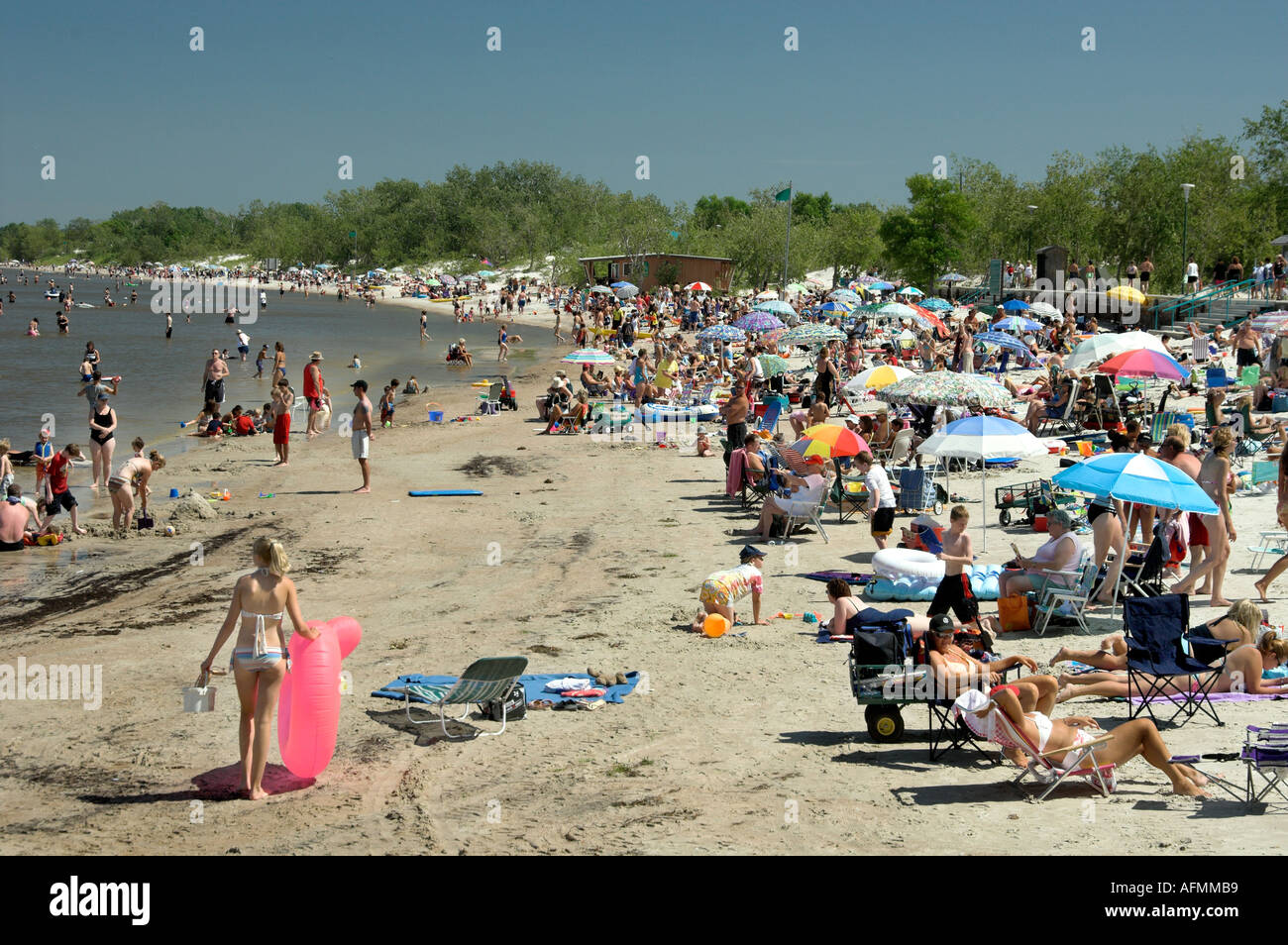 Beach scene with sunbathers and colorful umbrellas at Grand Beach ...