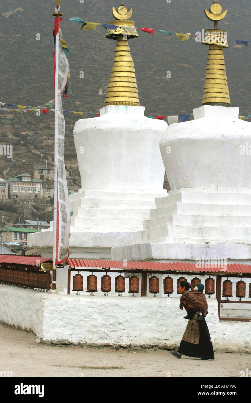 Mother praying and perambulating buddhist stupas with prayer wheels in ...