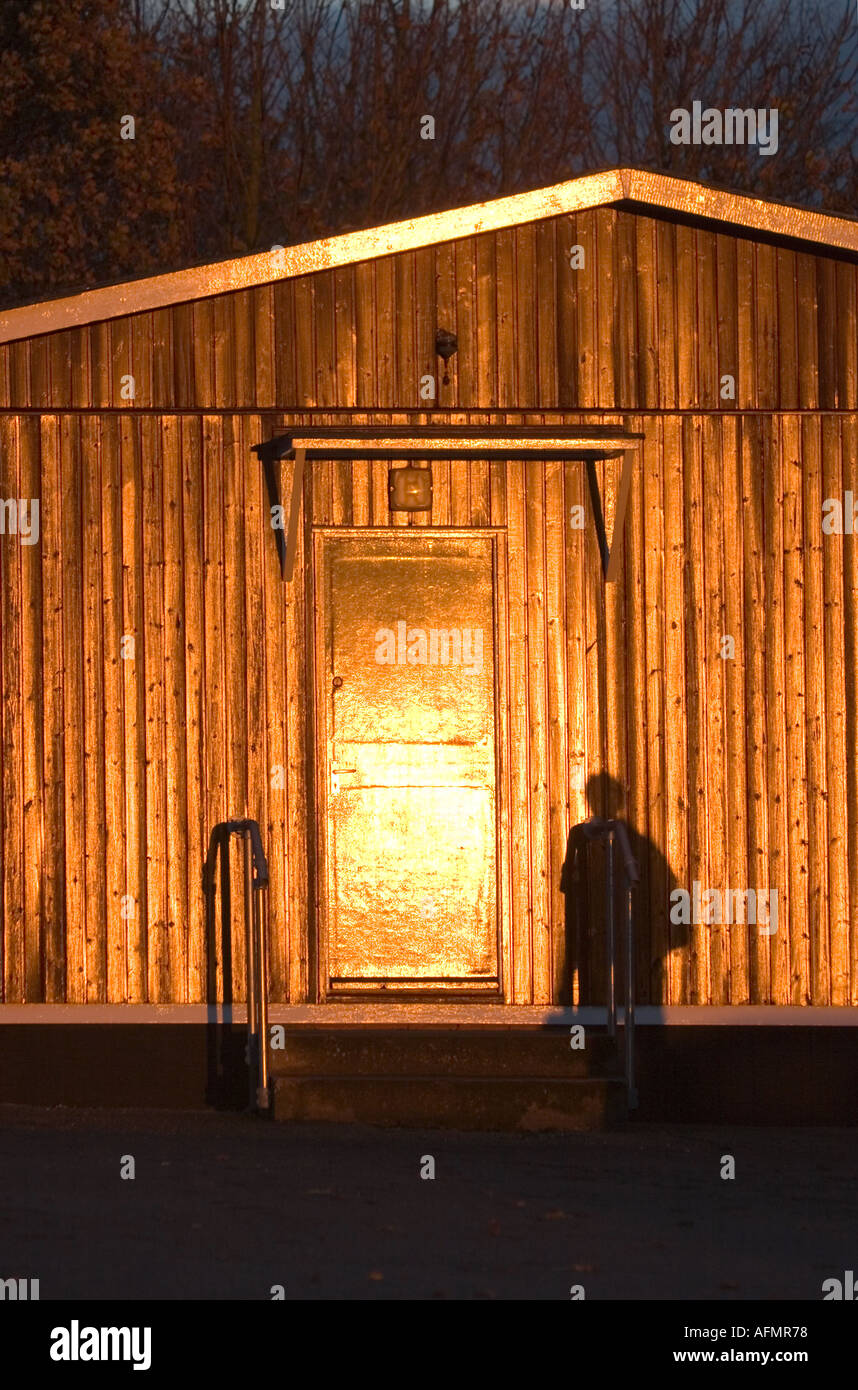 Shadow of a Person Approaching Sunlit Wooden Building at Dusk UK Stock ...