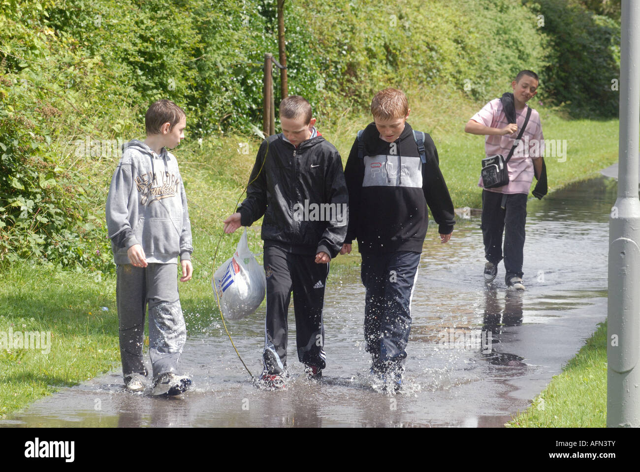 A group of young boys wade through a flooded path Stock Photo - Alamy