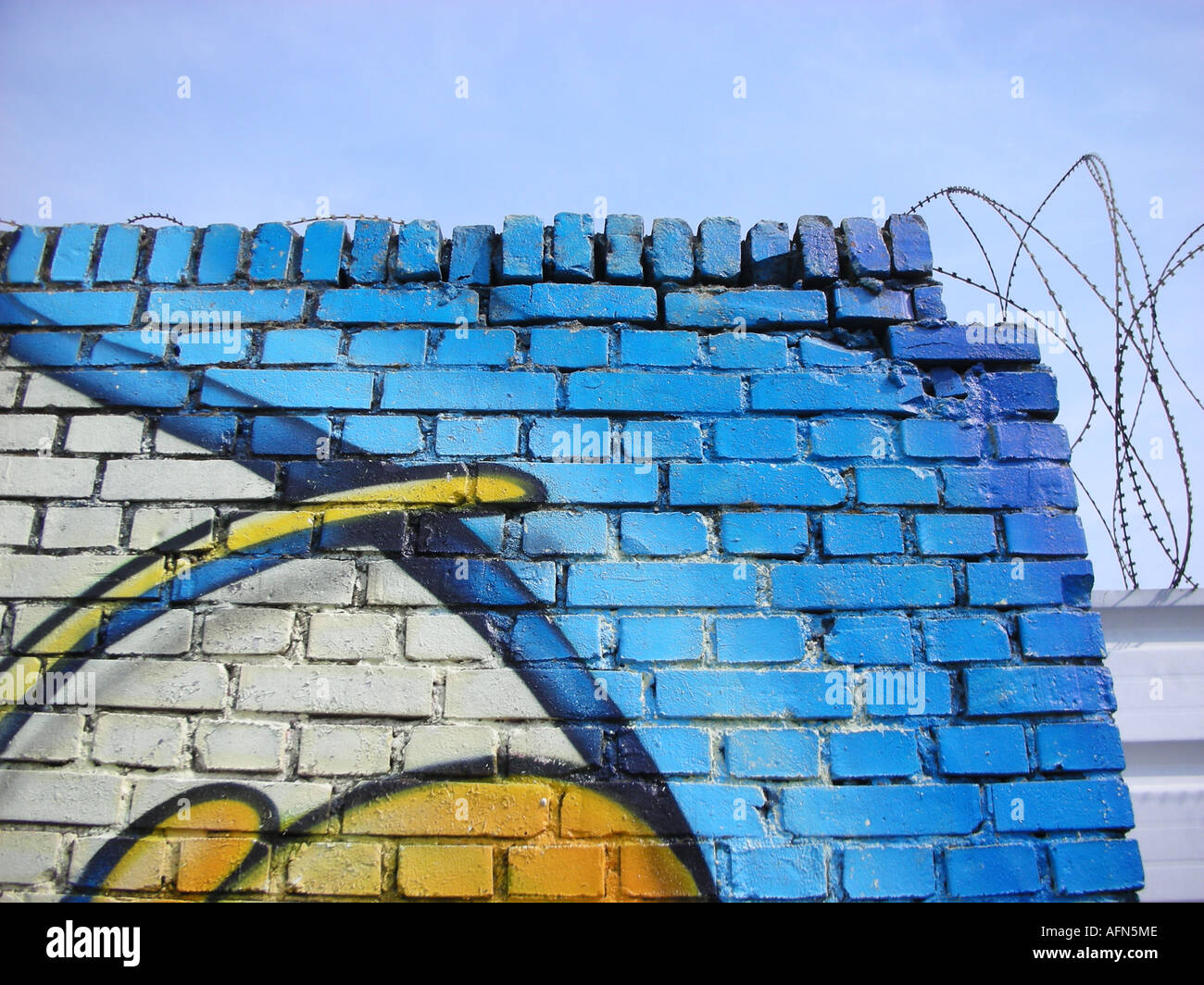 Colourful corner of graffiti covered brick wall with barbed wire and ...