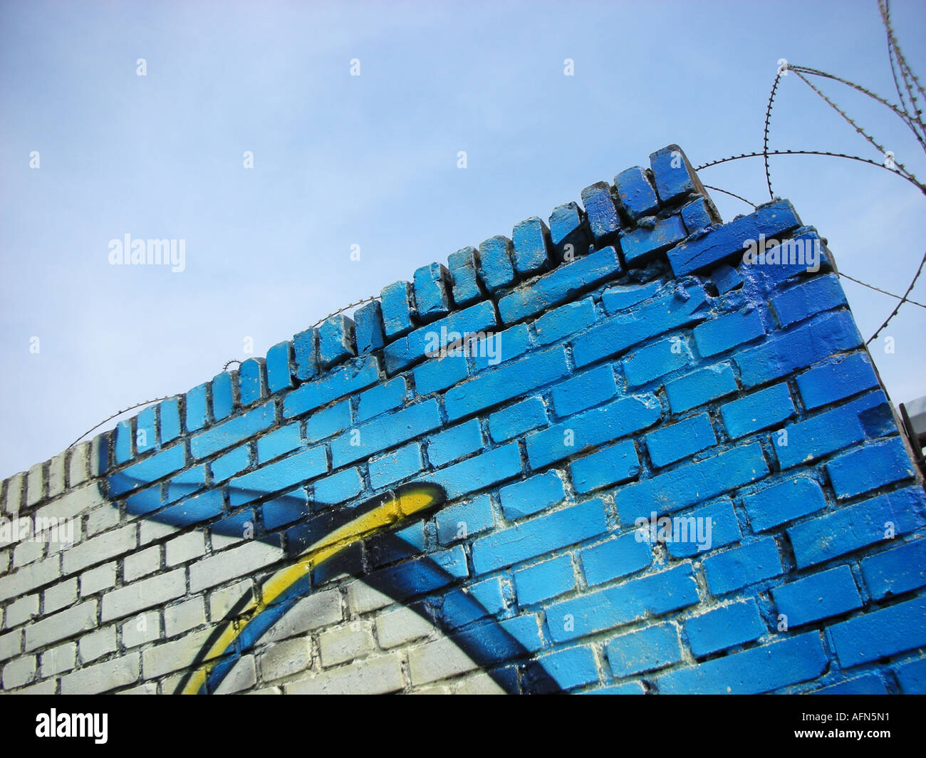 Colourful corner of graffiti covered brick wall with barbed wire and ...