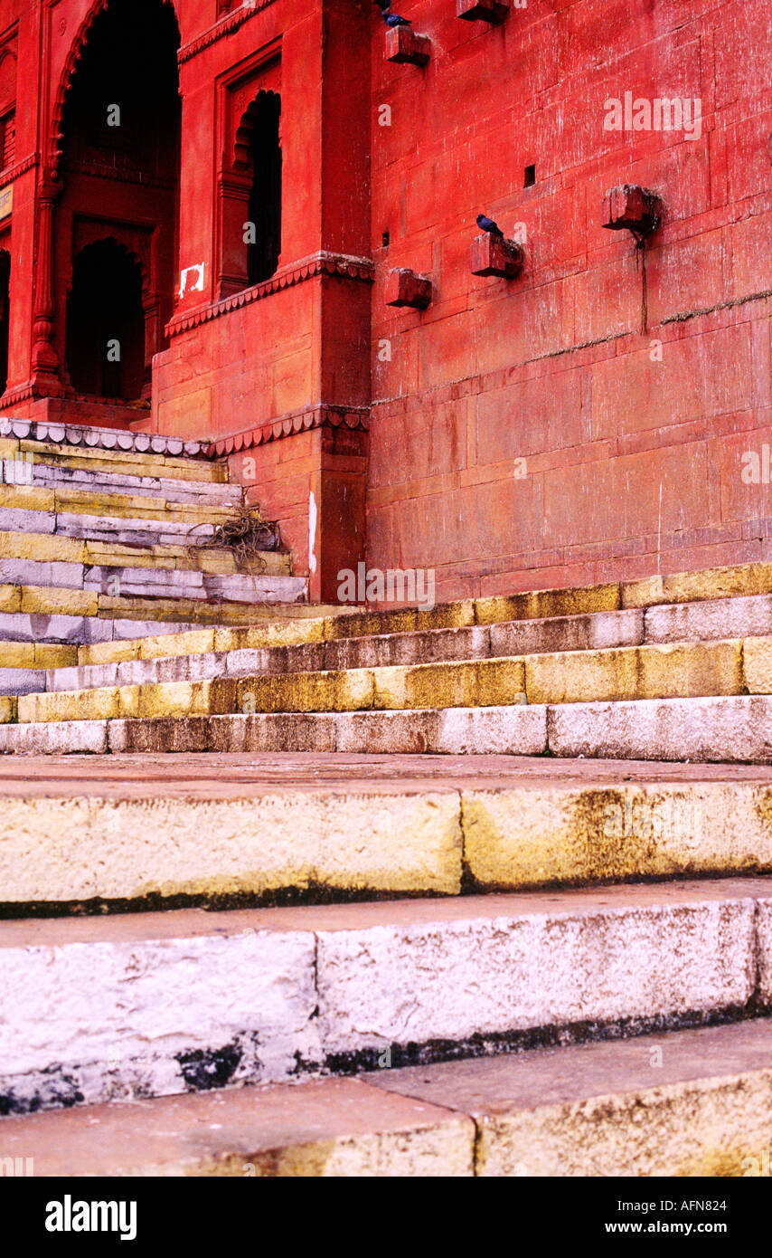 Many steep stairs to a bright red building on of the Ghat in Varanasi ...