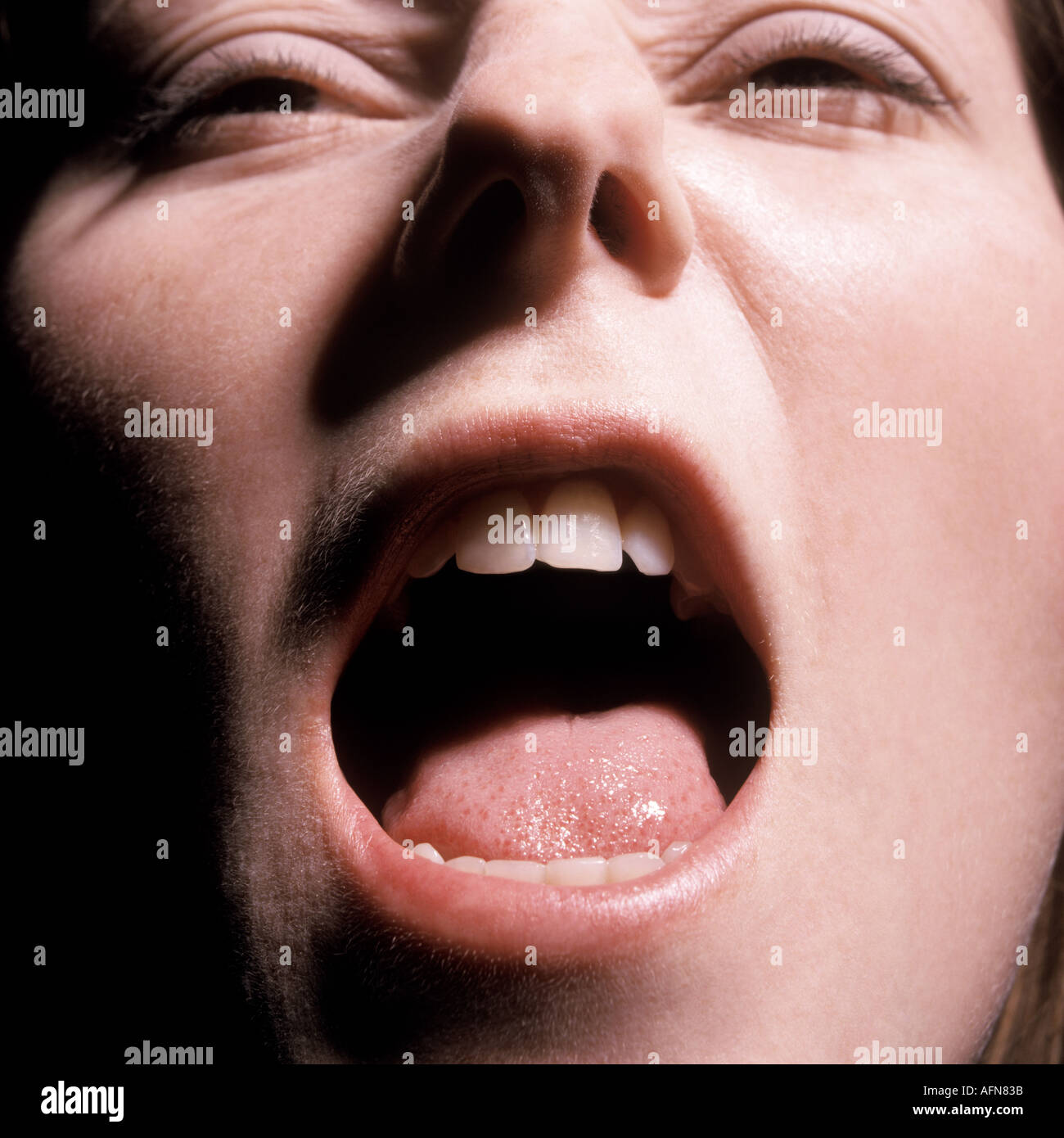 Close up of one woman female face with eyes almost shut and mouth wide ...