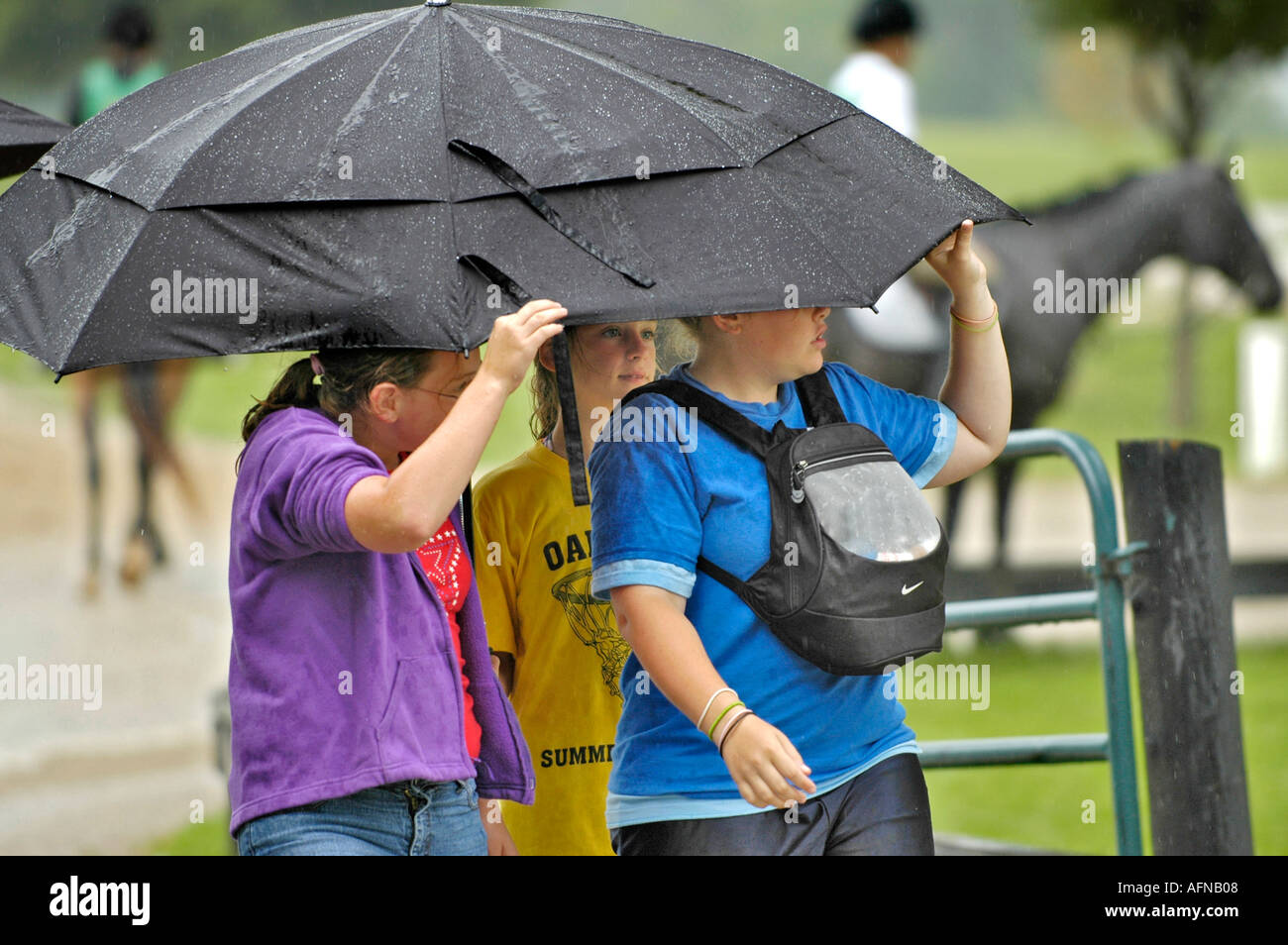 Girls protect themselves from a rain storm by covering their heads with ...