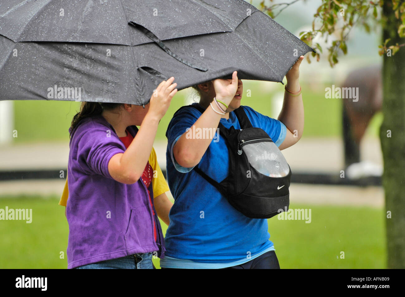 Girls protect themselves from a rain storm by covering their heads with ...