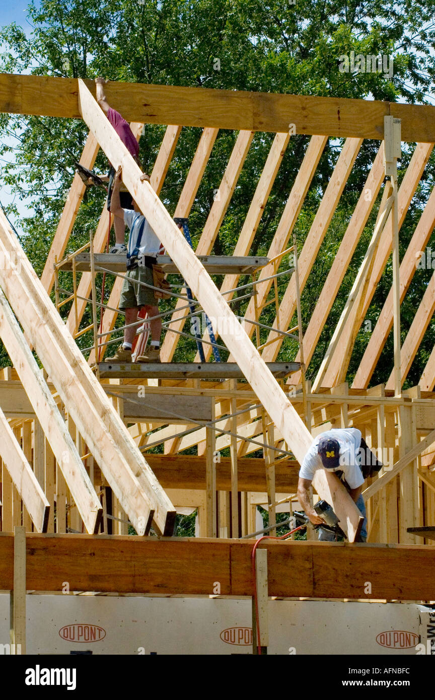 Two men frame the roof of a new home in a residential neighborhood ...