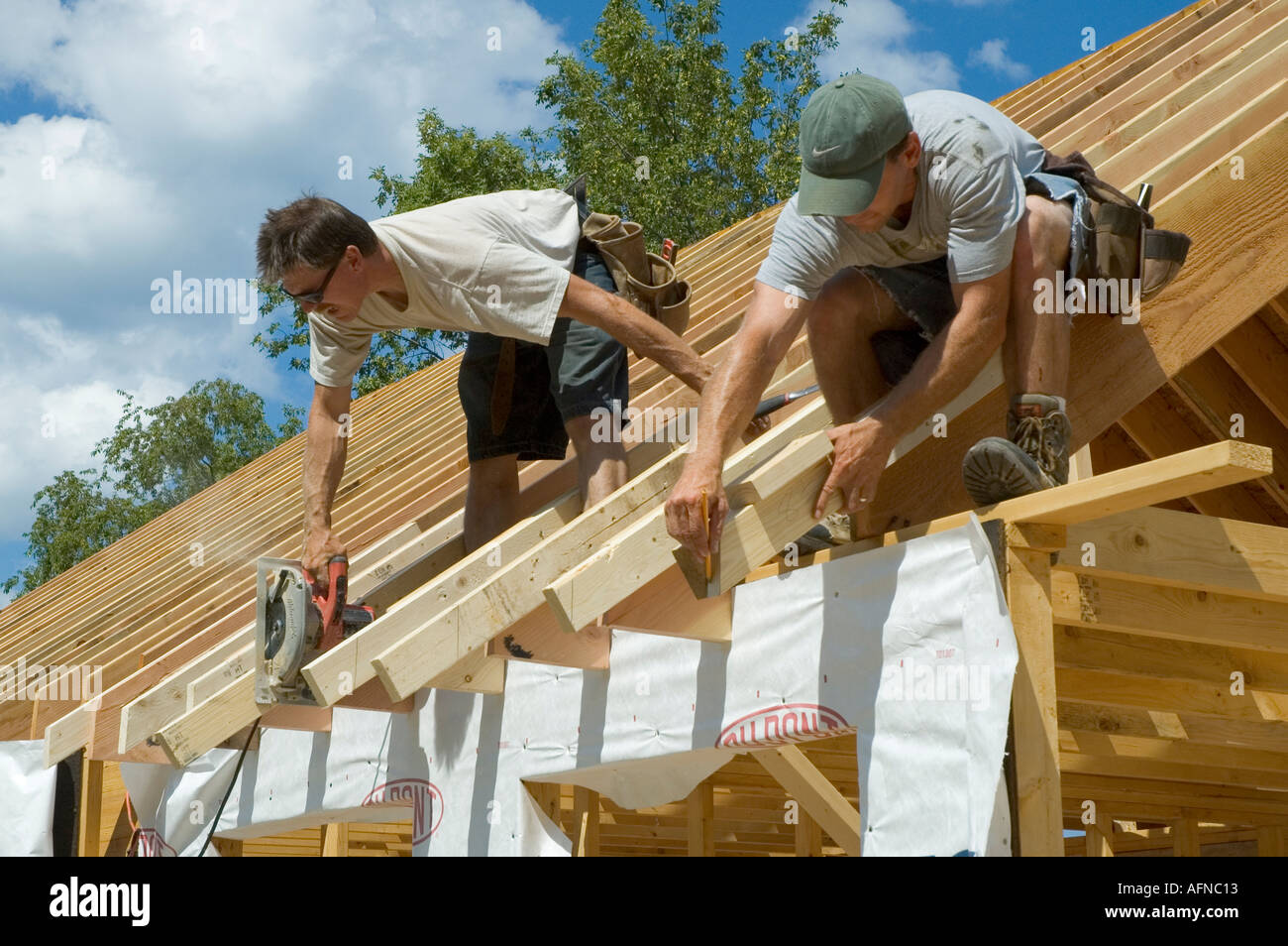 Two men frame the roof of a new home in a residential neighborhood ...