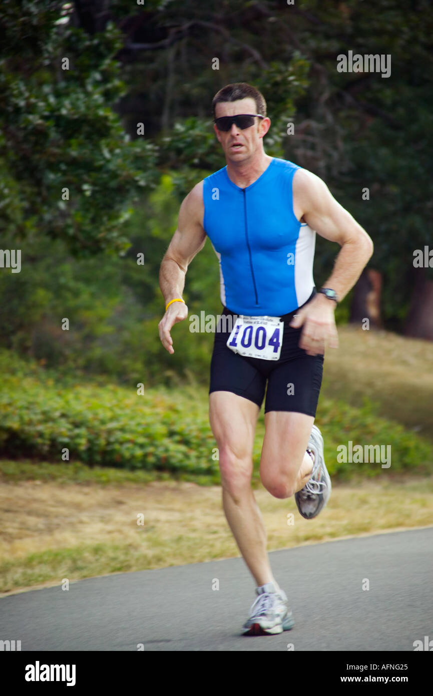 Man running final stage of triathlon Stock Photo - Alamy