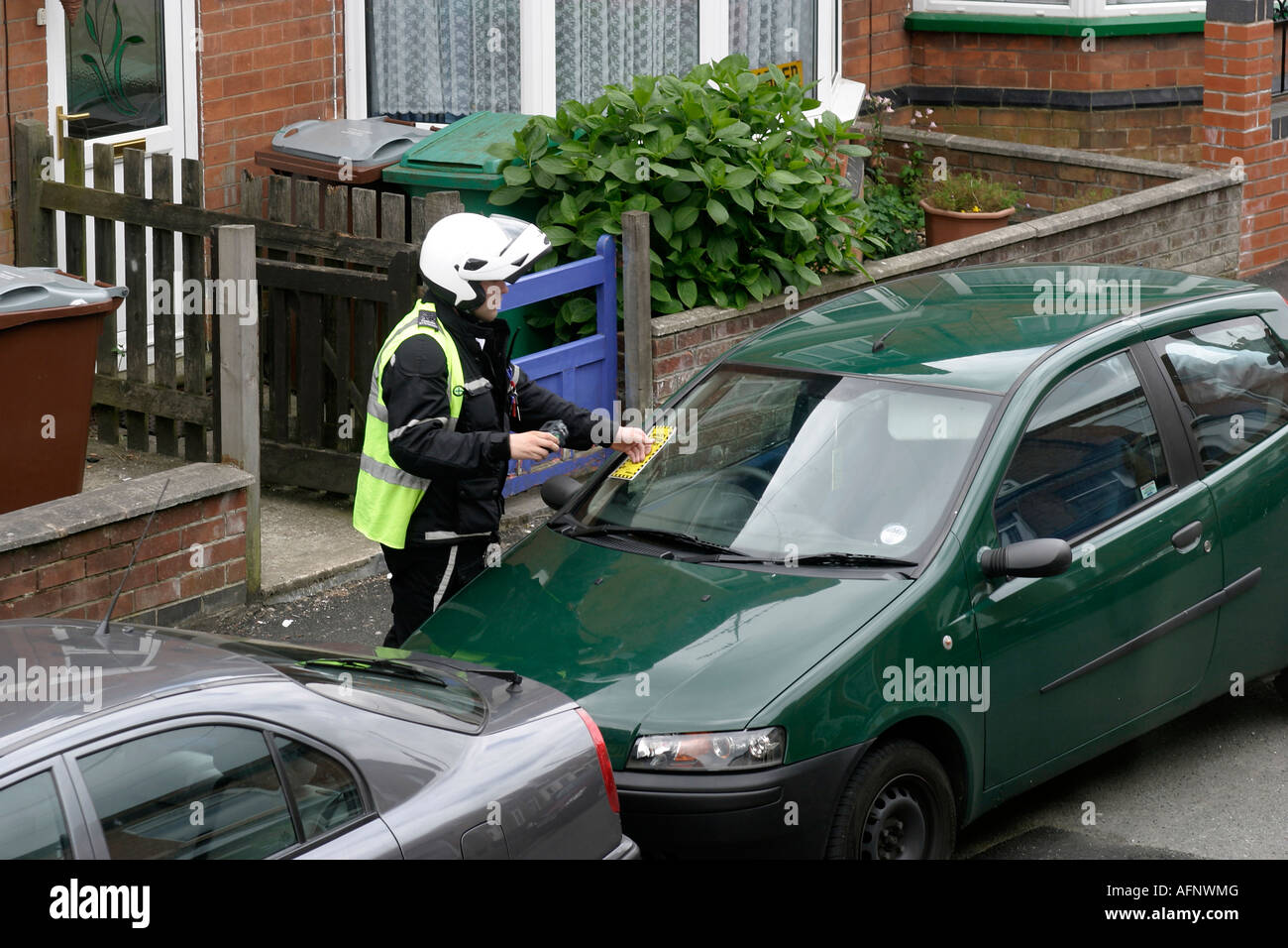 Traffic warden or parking attendant issuing a ticket to a car parked in ...