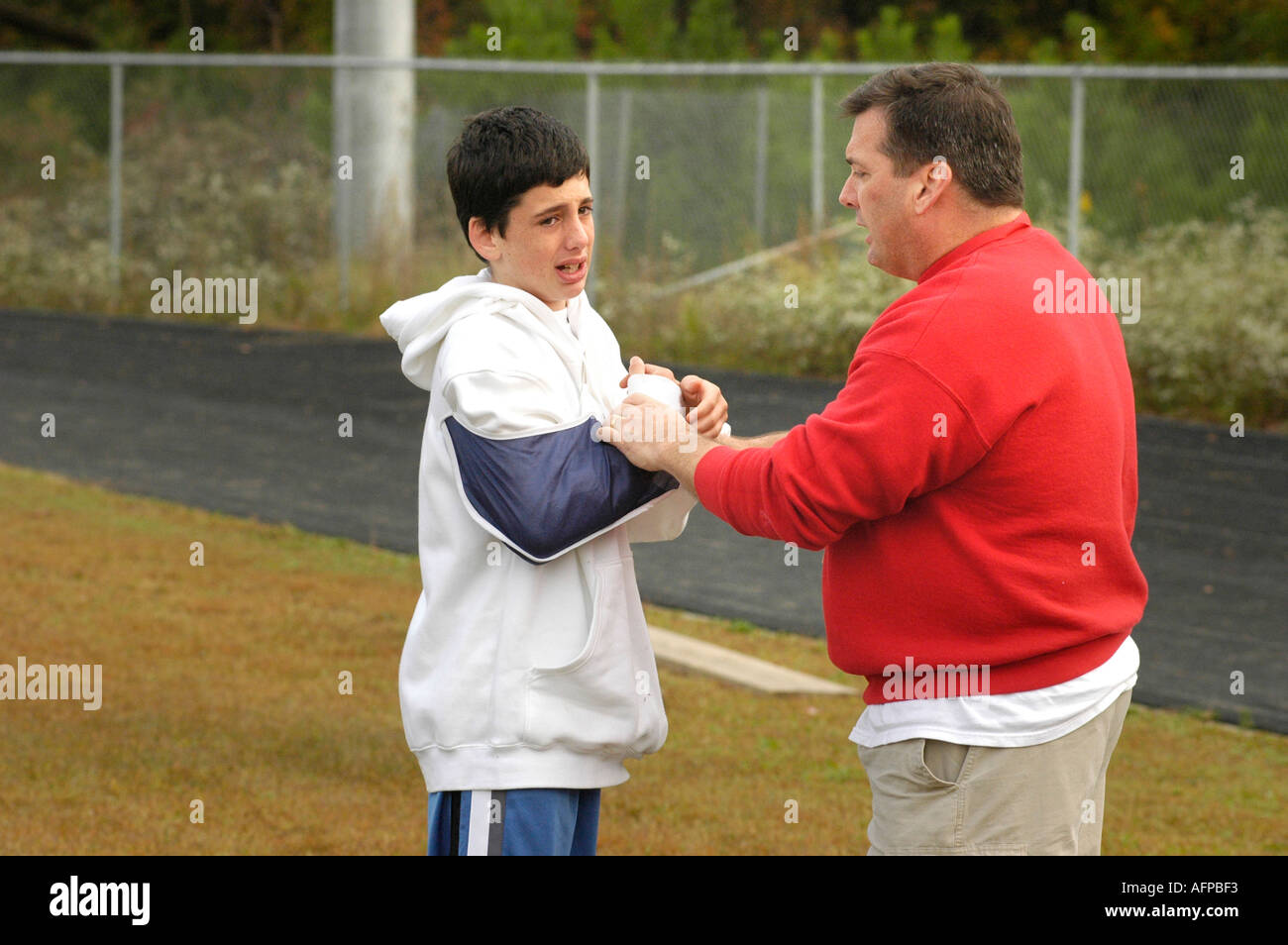 Injured young football player on bench with arm in cast from injury and ...