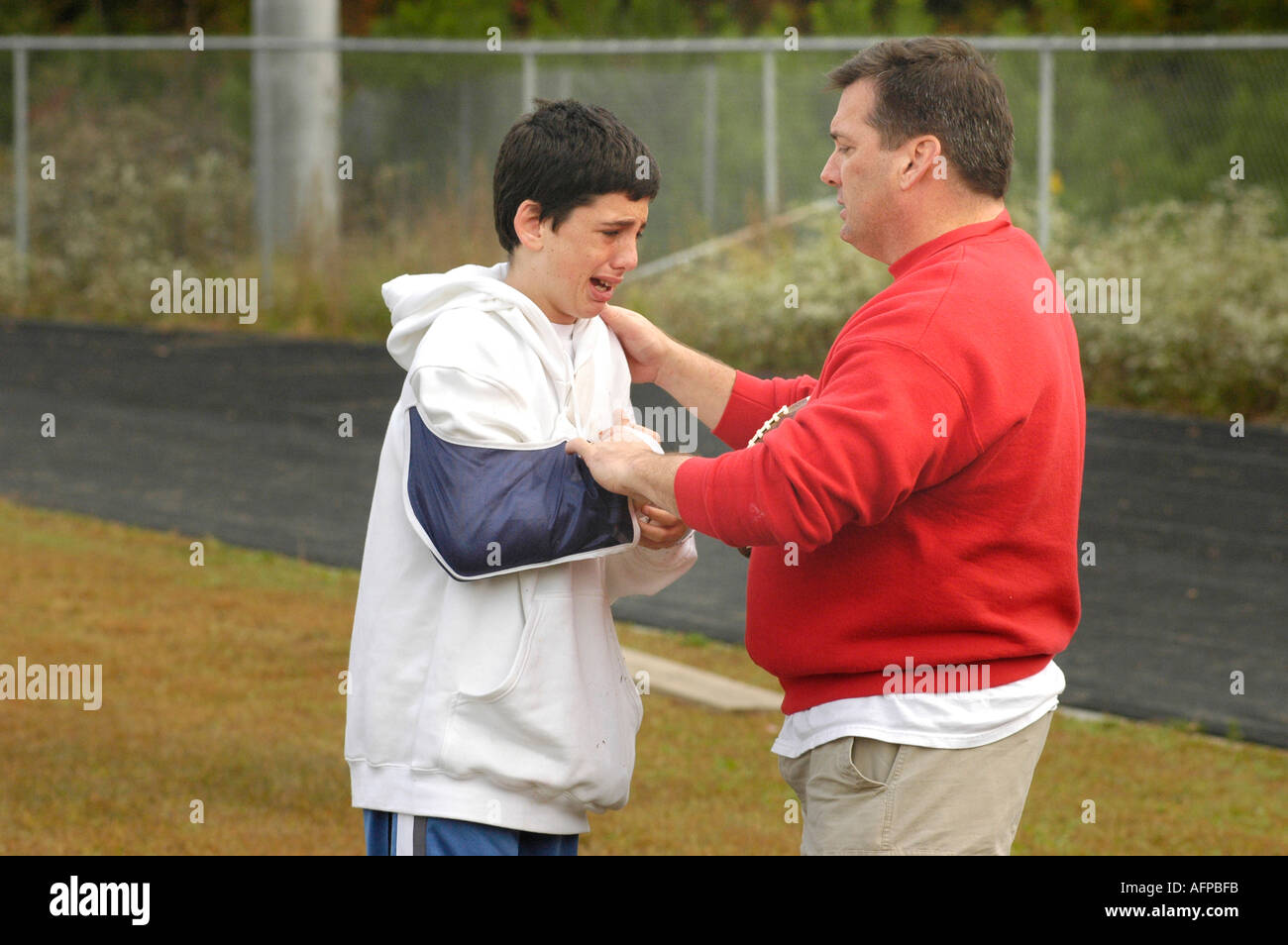 Injured young football player on bench with arm in cast from injury and ...
